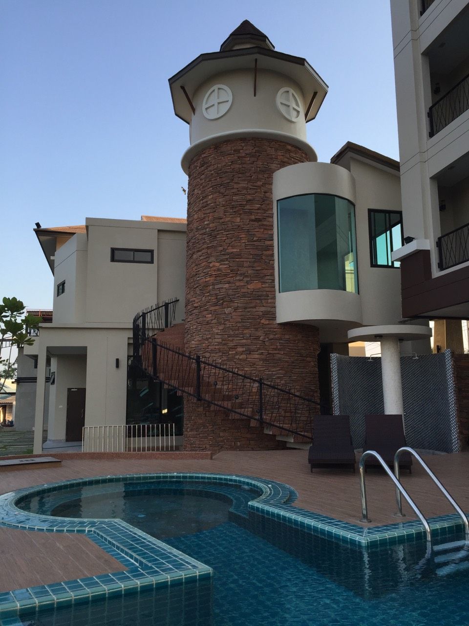 Um edifício moderno com uma torre, piscina e escadaria.