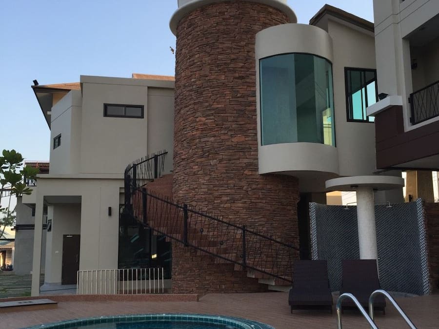 Um edifício moderno com uma torre, piscina e escadaria.