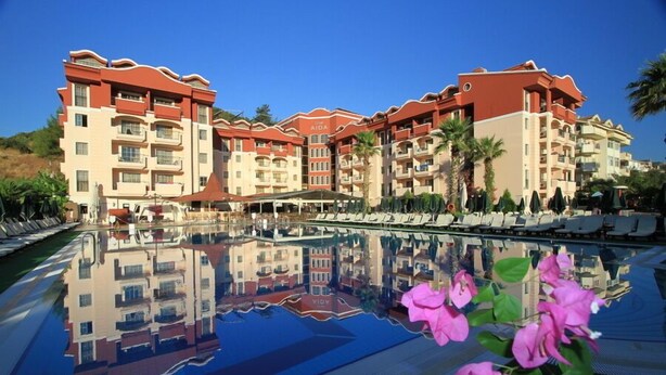 Um hotel com vários andares, varandas e área de piscina com espreguiçadeiras.