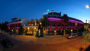 Hotel com design moderno, destacando uma placa visível e uma entrada bem iluminada.