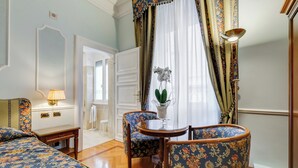 Quarto de hotel com cama, escrivaninha, cadeira, mesa e planta em vaso.