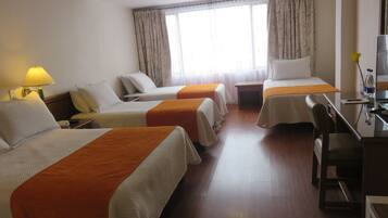 Quarto de hotel com duas camas, uma escrivaninha e uma cadeira.