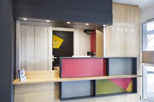 Uma receção com um letreiro 'Bienvenue Chez Vous', um balcão e vista para o interior.