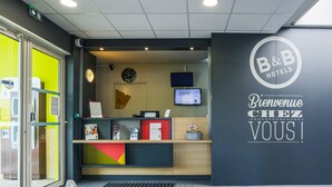 Uma área de recepção com design moderno, com um balcão de atendimento, um relógio e uma televisão.