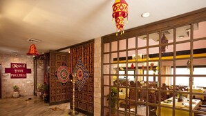 Restaurante com interior tradicional, apresentando piso de madeira, painéis decorativos na parede e lanternas penduradas.