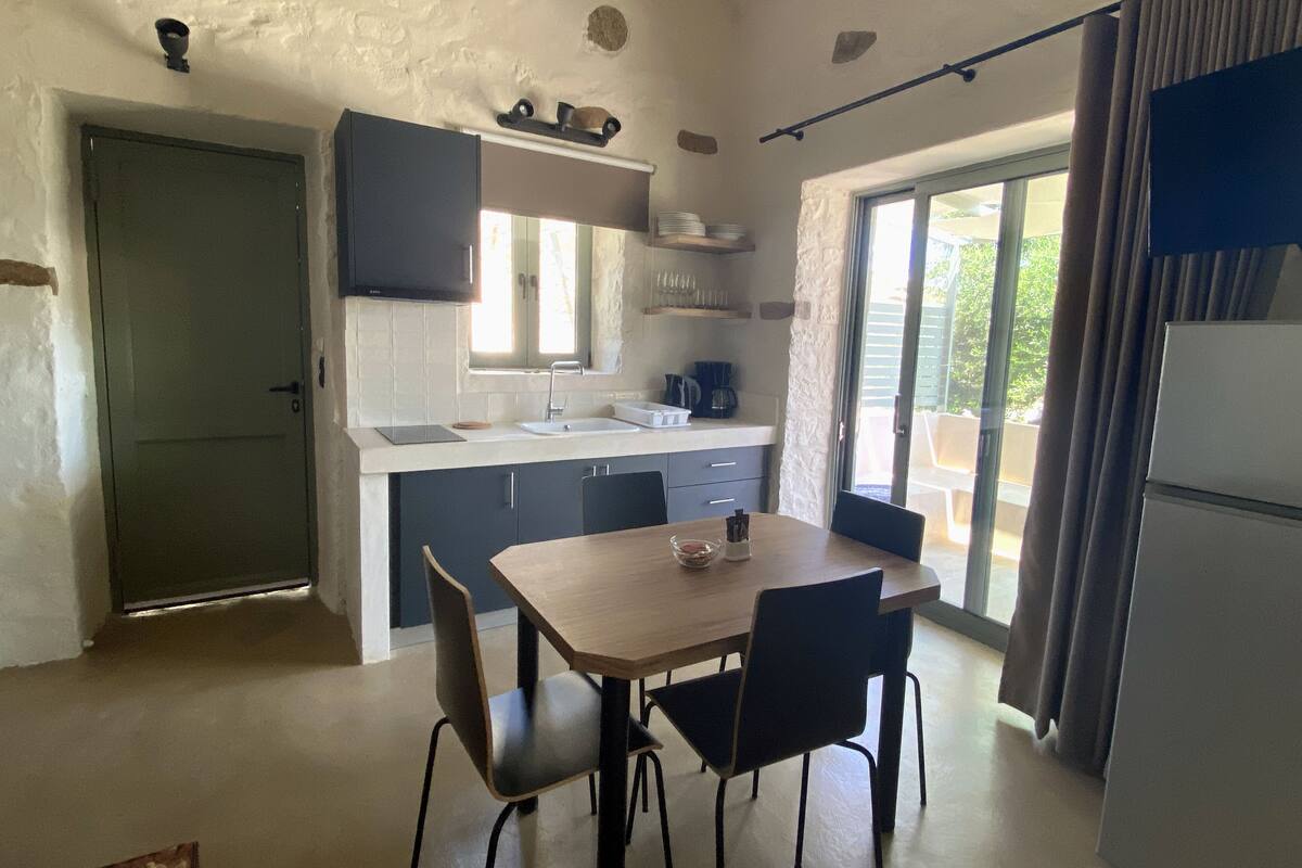Uma cozinha compacta com área de refeições, forno embutido e porta de vidro deslizante para uma varanda.