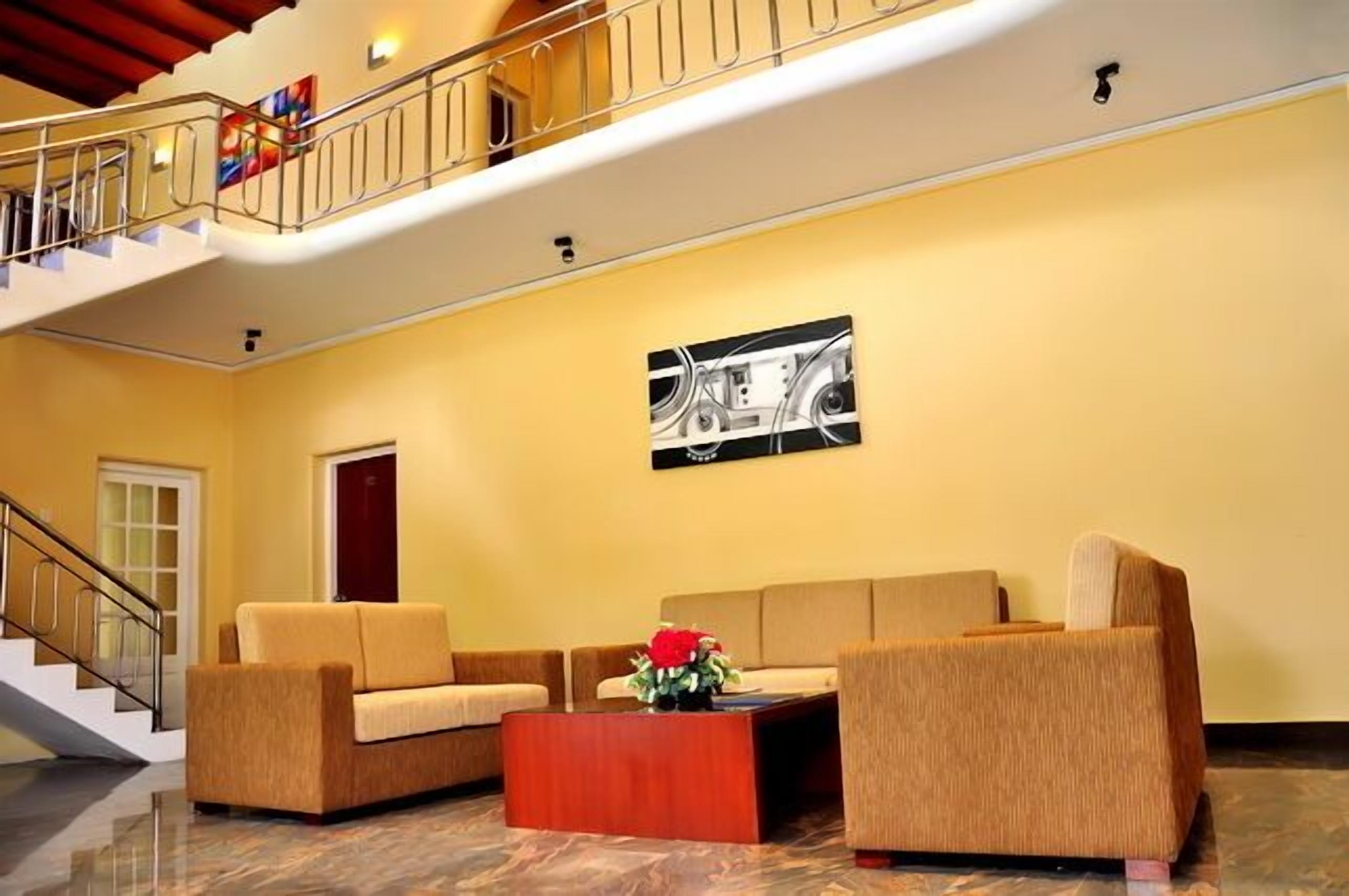 Um hall com escadaria, balcão de recepção e uma grande pintura abstrata na parede.