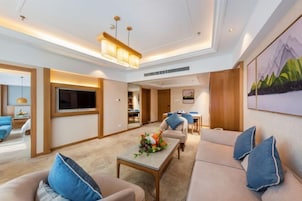 Uma sala de estar moderna com um conjunto de sofá, uma mesa de centro com um arranjo floral e uma televisão.