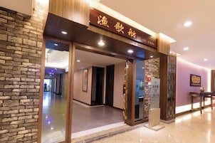 Entrada de hotel com fachada de pedra, arco de madeira e placa com caracteres chineses.