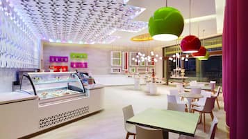Um café moderno com balcão central, área de estar e iluminação decorativa.