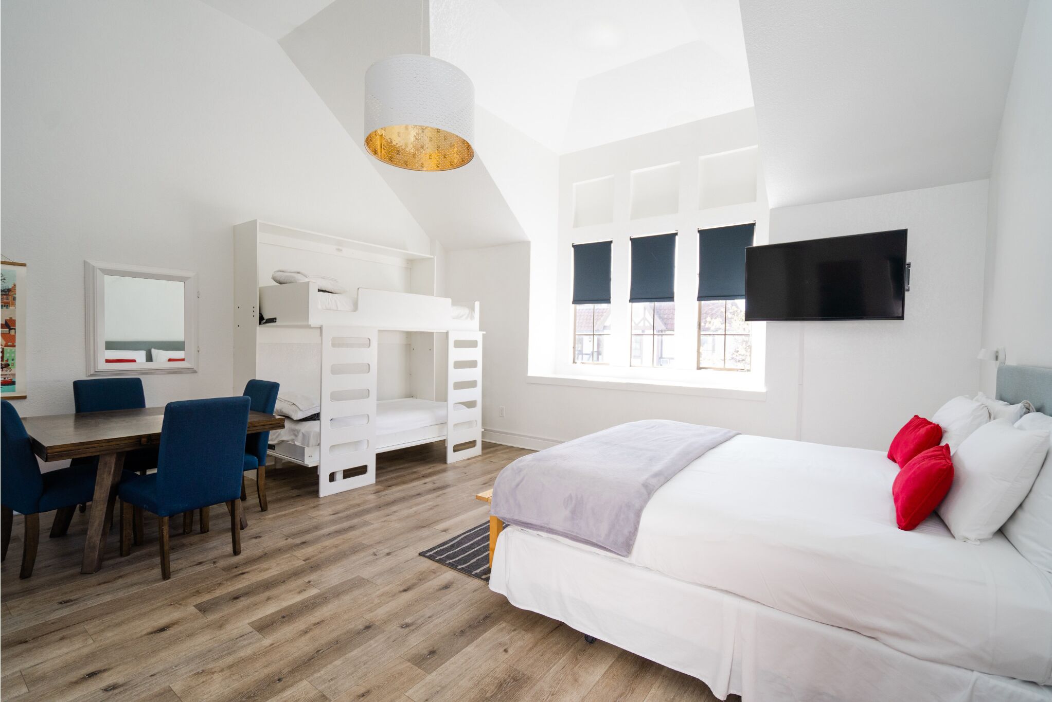 Quarto moderno com cama de solteiro, mesa de trabalho e televisão.