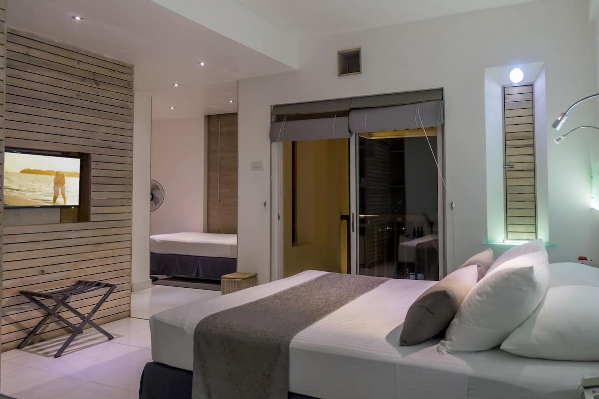 Quarto moderno com cama, mesa de cabeceira e televisão fixada na parede.