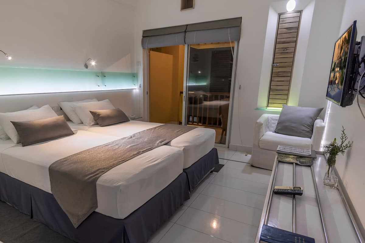 Quarto de hotel moderno com uma cama grande, mesas de cabeceira, uma escrivaninha e uma cadeira.