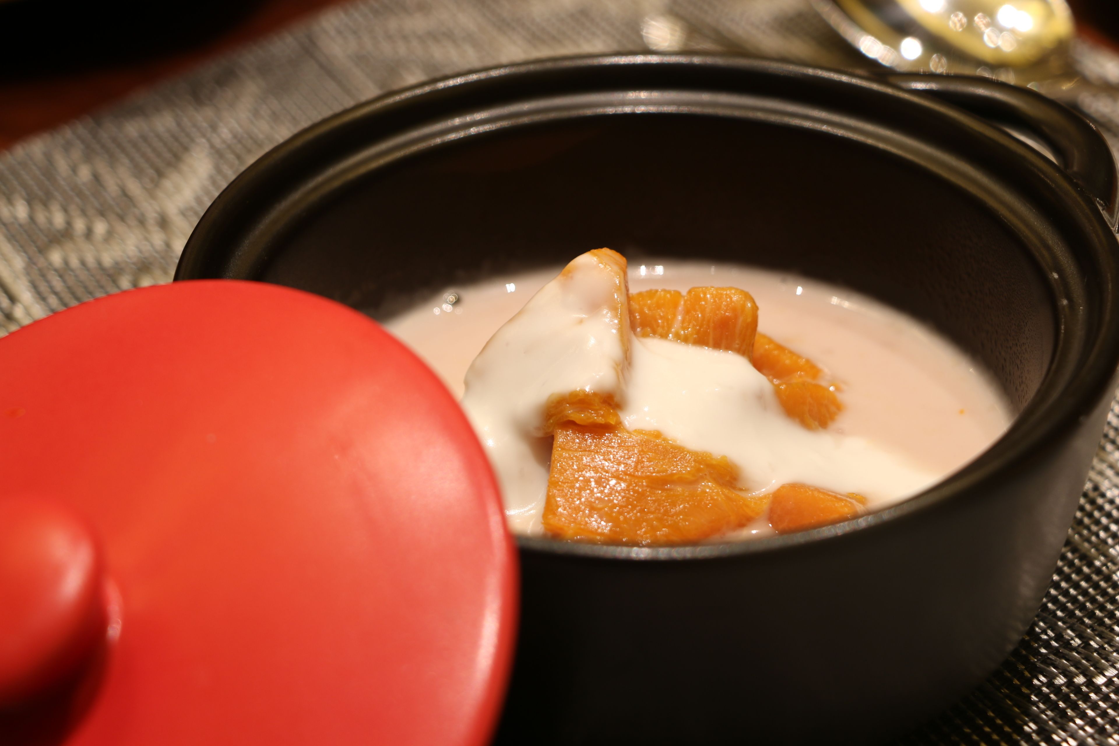 Uma tigela de sopa com tampa vermelha.