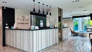 Uma área de recepção de hotel com balcão de mármore, luminárias pendentes e vista para o exterior.