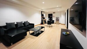 Uma sala de estar moderna com um sofá preto, uma mesa de centro e um espaço de jantar com cadeiras e uma mesa.