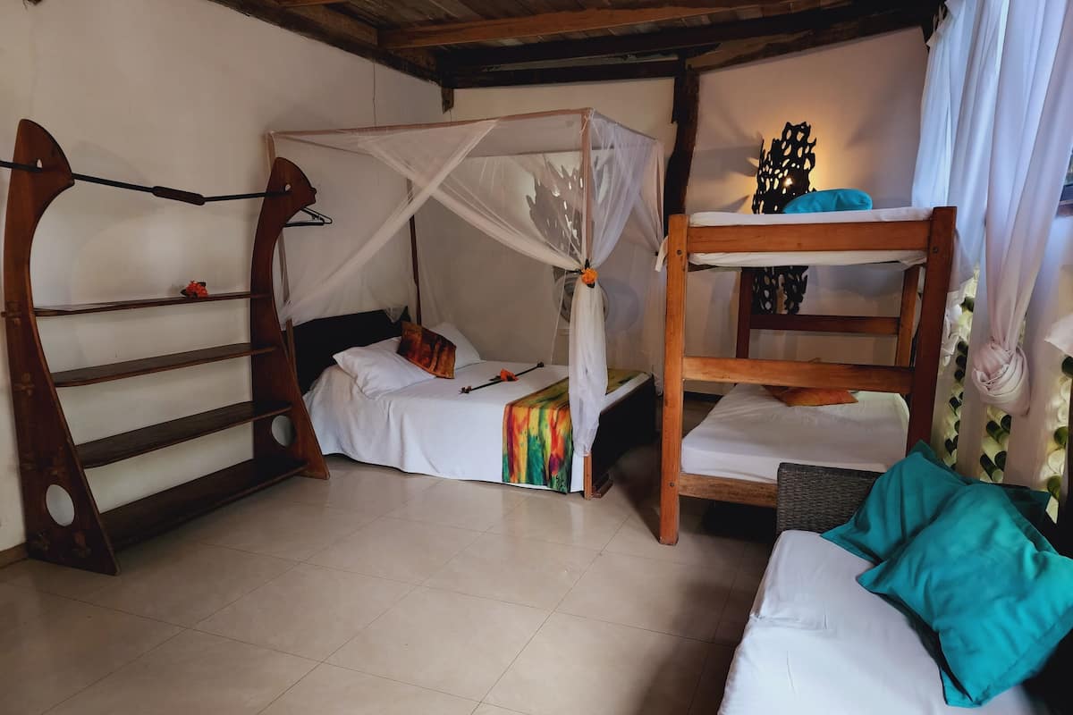 Quarto com uma cama beliche de madeira, um sofá-cama e uma estante.