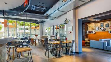 Interior moderno de café com mesas, cadeiras, um relógio e vista para o exterior.