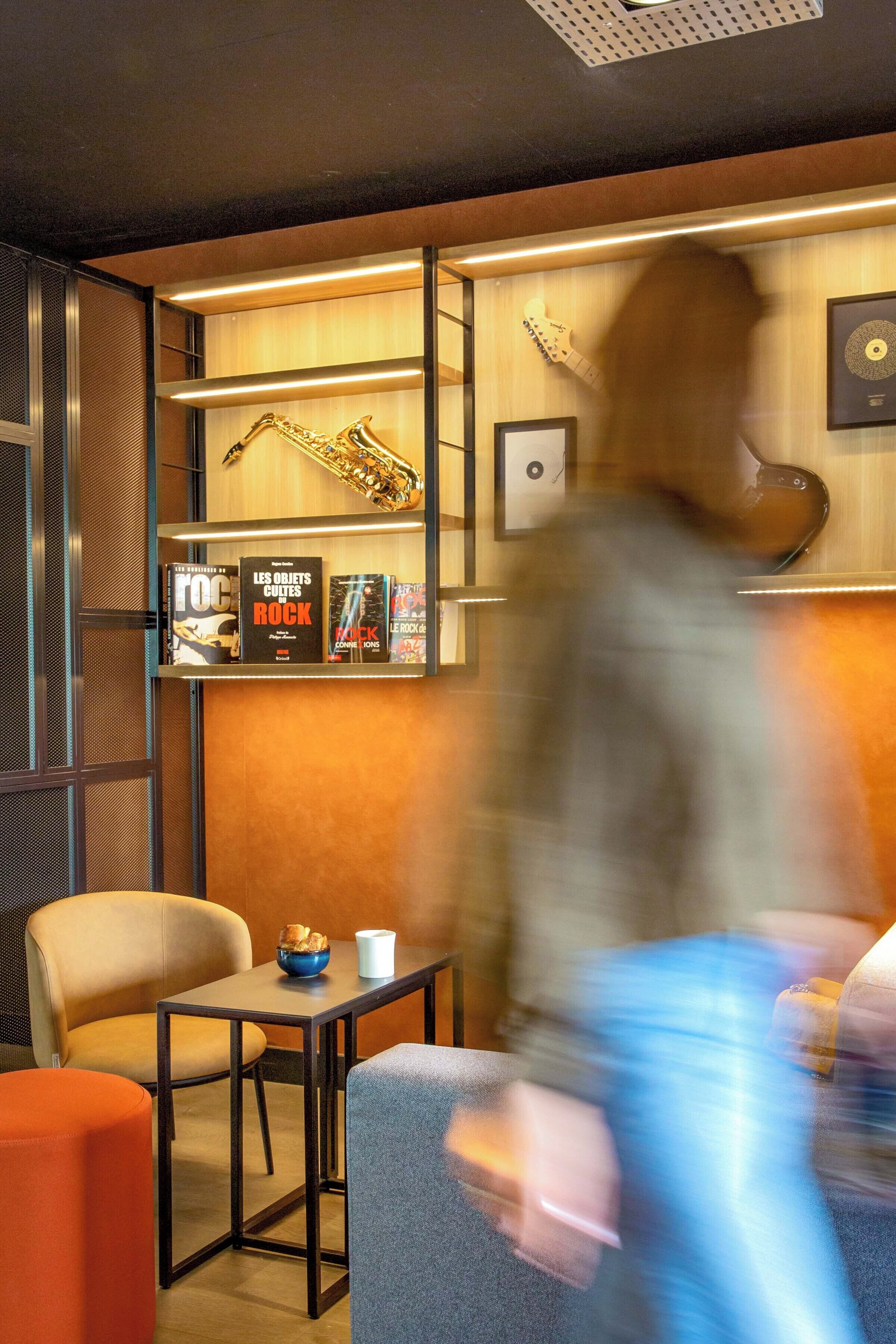 Um interior moderno com um sofá, uma mesa com uma tigela e uma xícara, e uma estante com livros e um saxofone.