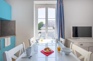 Uma área de refeições com uma mesa posta para o café da manhã, incluindo um prato de doces e um copo de suco de laranja.