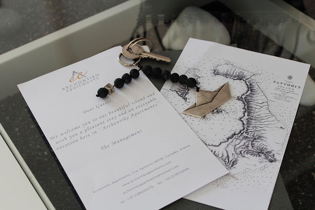 Carta de boas-vindas do Archontiko Apartments, com informações de contato e um mapa de Santorini, Grécia.