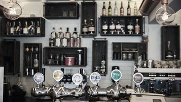 Uma área de bar com várias torneiras identificadas por nomes de cerveja e uma variedade de garrafas nas prateleiras ao fundo.