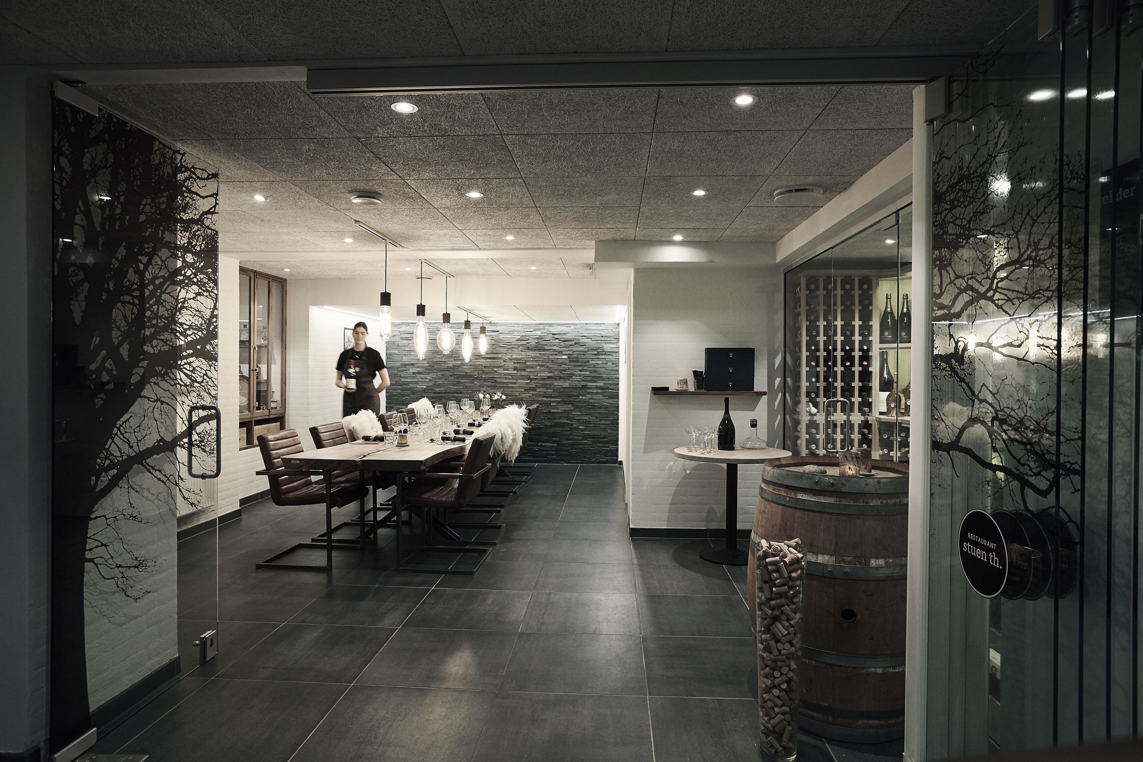 Uma sala de jantar moderna com uma mesa comprida, cadeiras e uma estante para vinhos.