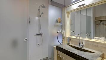 Casa de banho moderna com cabine de duche em vidro, toucador com bancada de mármore e espelho grande.