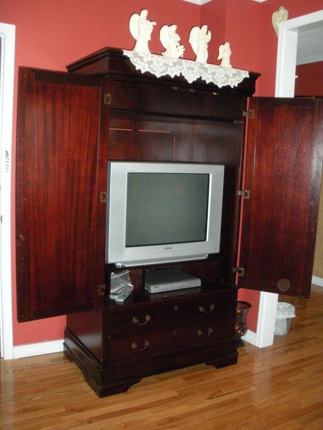 Centro de entretenimento de madeira com televisão, leitor de DVD e gavetas.
