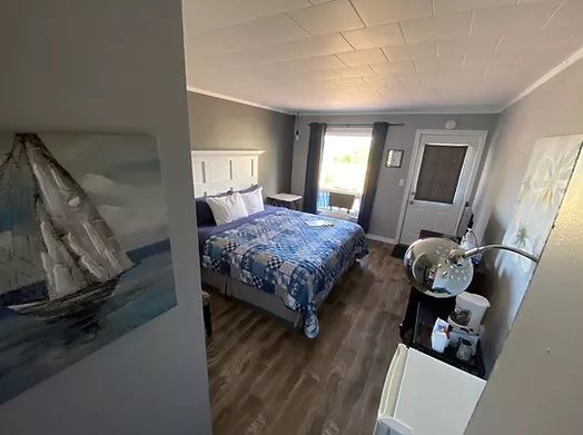 Quarto com cama, mesa de cabeceira, espelho e porta.