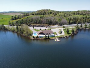 Um imóvel à beira do lago com uma casa grande, piscina e barcos atracados.