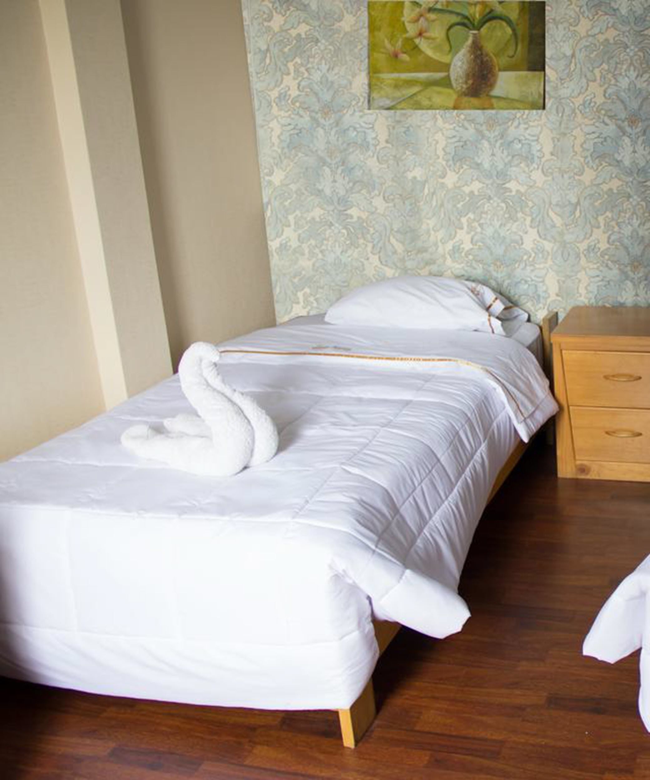 Cama bem arrumada com lençóis brancos e arranjo de toalha em formato de cisne.