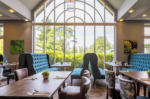 Restaurante com tetos altos, janelas amplas e vista para o verde.
