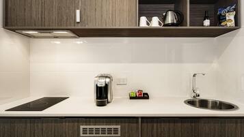 Cozinha moderna com cafeteira, chaleira e bule na bancada.