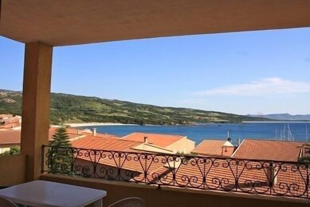 Varanda com vista para a costa, com edifícios em terraços e céu claro.