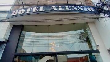 Um hotel com design moderno, destacando uma placa com o nome 'HOTEL ALESSIO'.