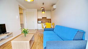 Uma sala de estar moderna com um sofá azul, mesa de centro de madeira e uma TV.