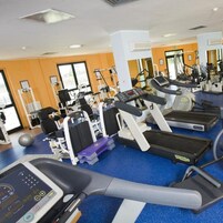 Uma academia com esteiras, elípticos e equipamentos de musculação.