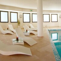 Área de spa com espreguiçadeiras, piscina e planta em vaso.
