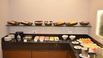 Disposição de buffet com diversos alimentos e utensílios.