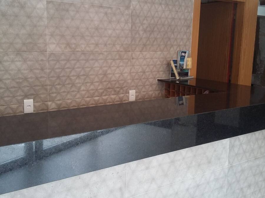 Uma área de recepção com balcão preto, azulejos estampados e um armário de madeira.