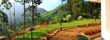 Um jardim ajardinado com um caminho, vasos de plantas e vista para uma paisagem montanhosa.