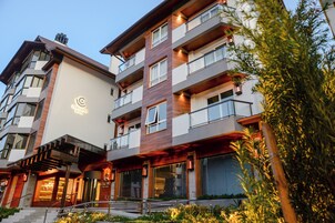 Um hotel de vários andares com design moderno, com varandas, janelas amplas e uma entrada bem iluminada.