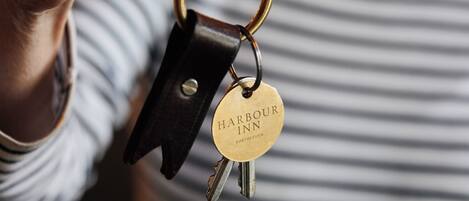 Uma pessoa segurando um conjunto de chaves com um chaveiro identificado como 'Harbour Inn'.