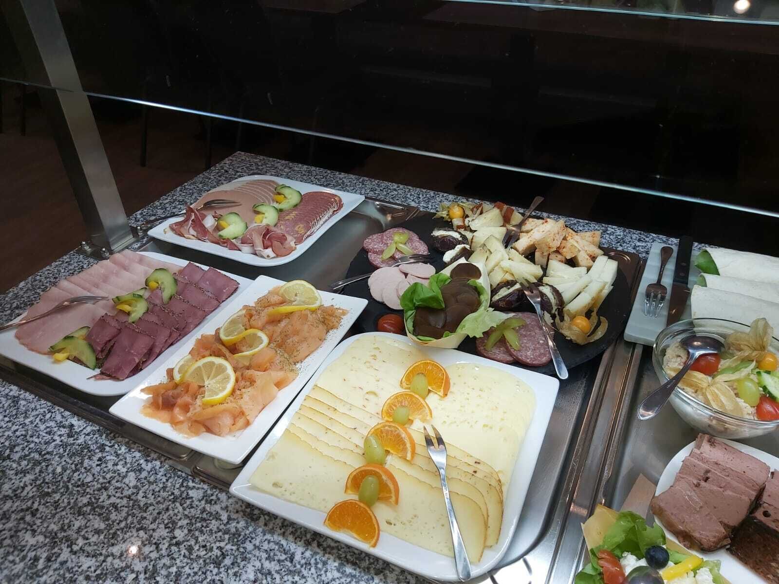 Buffet com diversos frios, queijos e saladas.