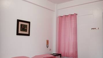 Quarto com duas camas, um ventilador de teto, um quadro na parede, um telefone e uma cortina rosa.