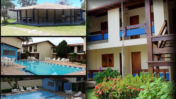 Um hotel com área de estar coberta ao ar livre, piscina e um jardim com plantas floridas.
