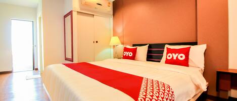 Quarto de hotel com uma cama grande, um guarda-roupa, um ar condicionado e uma lâmpada.