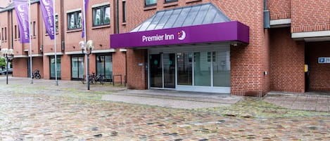 Edifício de tijolos com toldo roxo identificado como 'Premier Inn'.