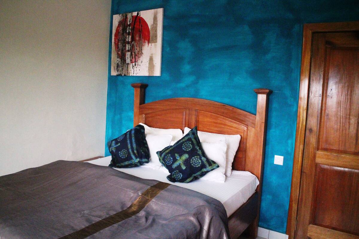 Uma cama com cabeceira de madeira, duas almofadas e um cobertor.